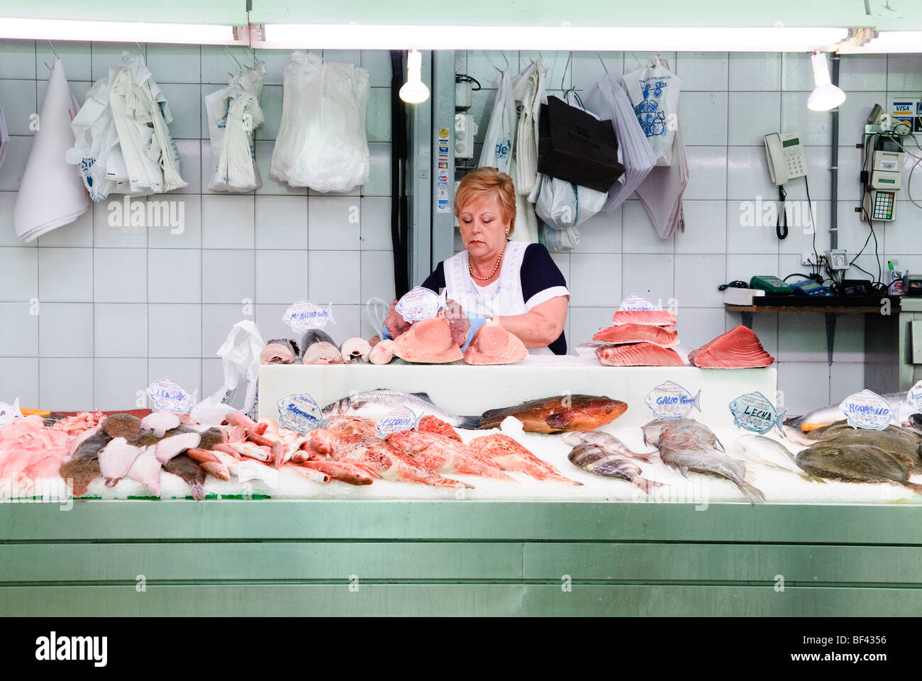 female fishmonger handles fish at stall stall in the central market ...