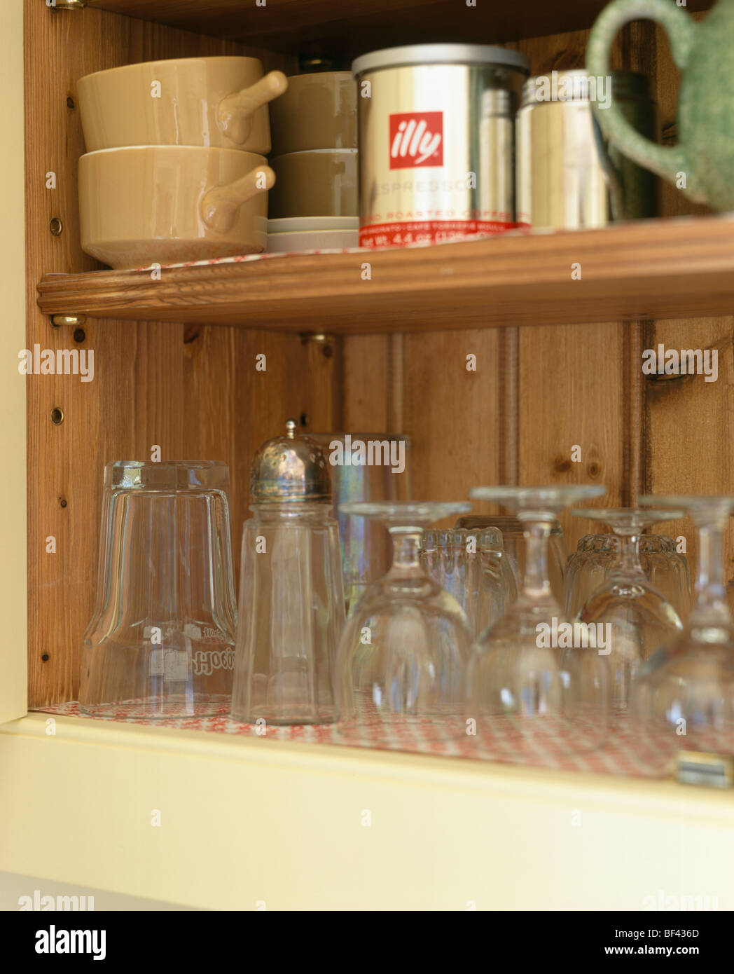 Close-up of wine glasses and old glass sugar sifter in kitchen cupboard ...