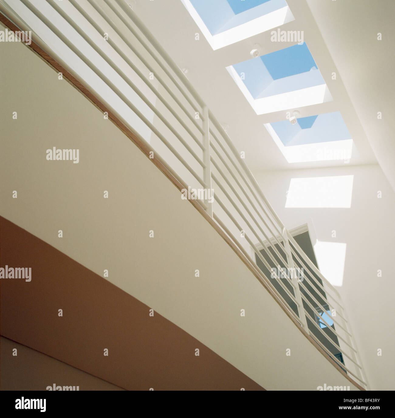 Looking up at metal walkway and glass skylights in modern architectural ...