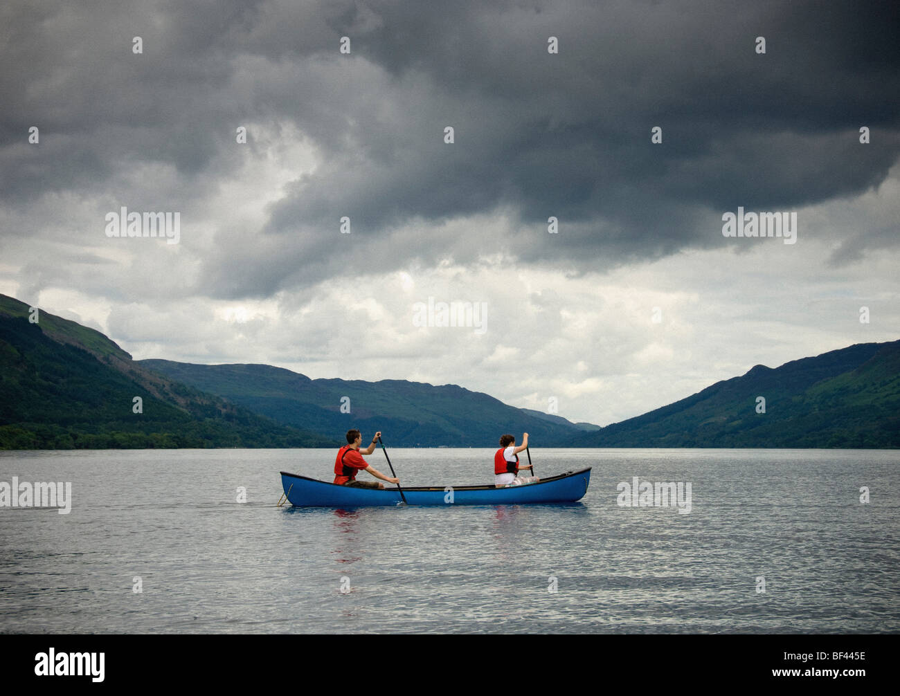 Young caucasian man and woman paddling a Canadian canoe on Loch Earn ...