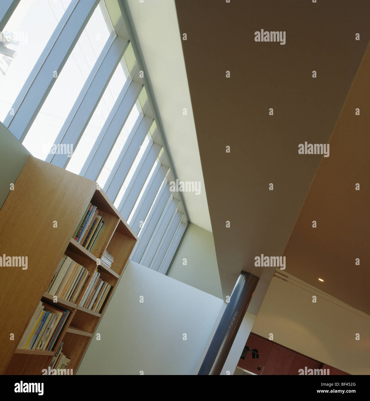Looking up at bookcase and floor-to-ceiling windows in modern living ...