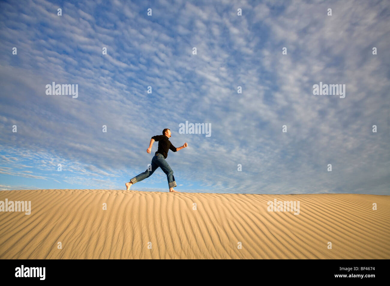 Man running on a sand dune Stock Photo - Alamy