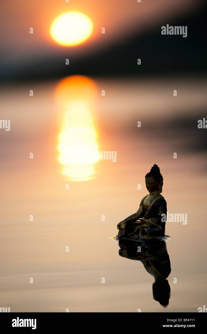 Silhouette of Buddha statue floating on calm still water surface with ...