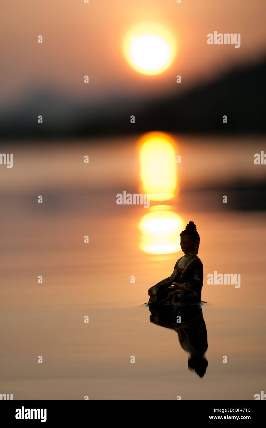 Silhouette of Buddha statue floating on calm still water surface with ...