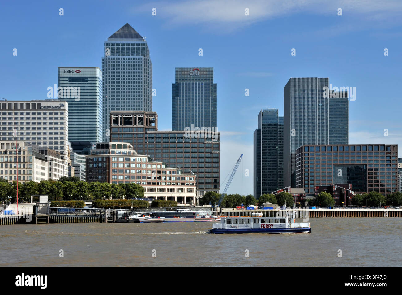 Canary Wharf skyline in London Docklands beyond River Thames with ferry ...