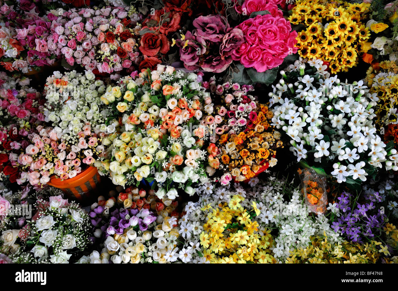 bunches of colorful colourful plastic fake artificial flowers blooms on ...