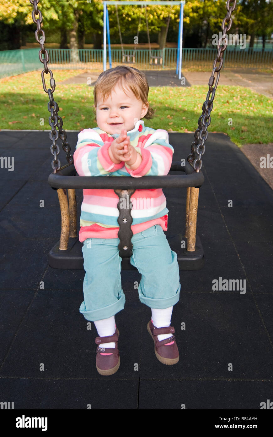 Vertical close up portrait of a little girl smiling and clapping whilst ...