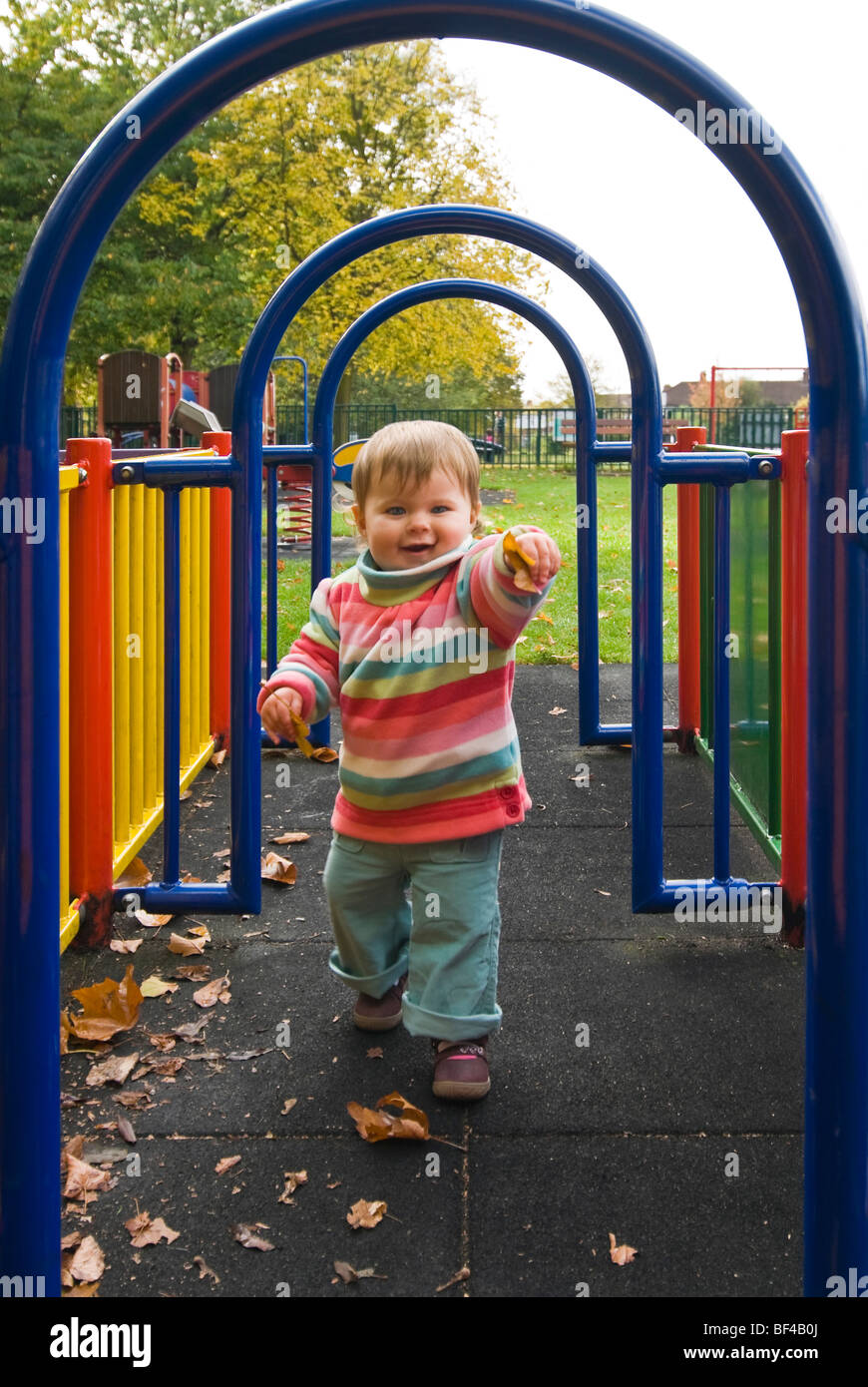 Vertical portrait of a baby girl toddling through a tubular maze with ...