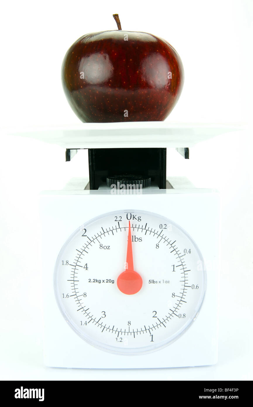 A red apple and a set of scales isolated against a white background ...
