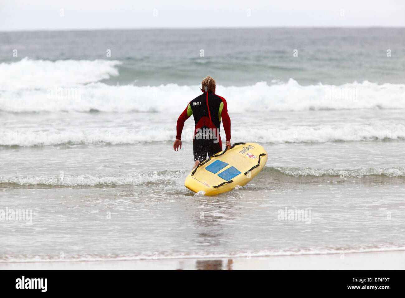 Male Lifeguard Running Into Sea with surf rescue board Stock Photo - Alamy