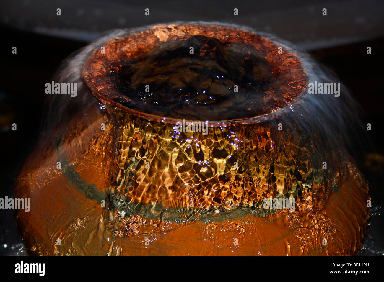 water spilling out from pot, looks like indian pot, in light ,Ceramic ...