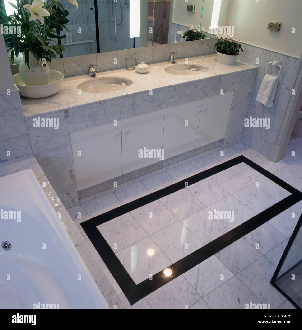 Black tiled border on marble tiled floor in modern bathroom with double ...