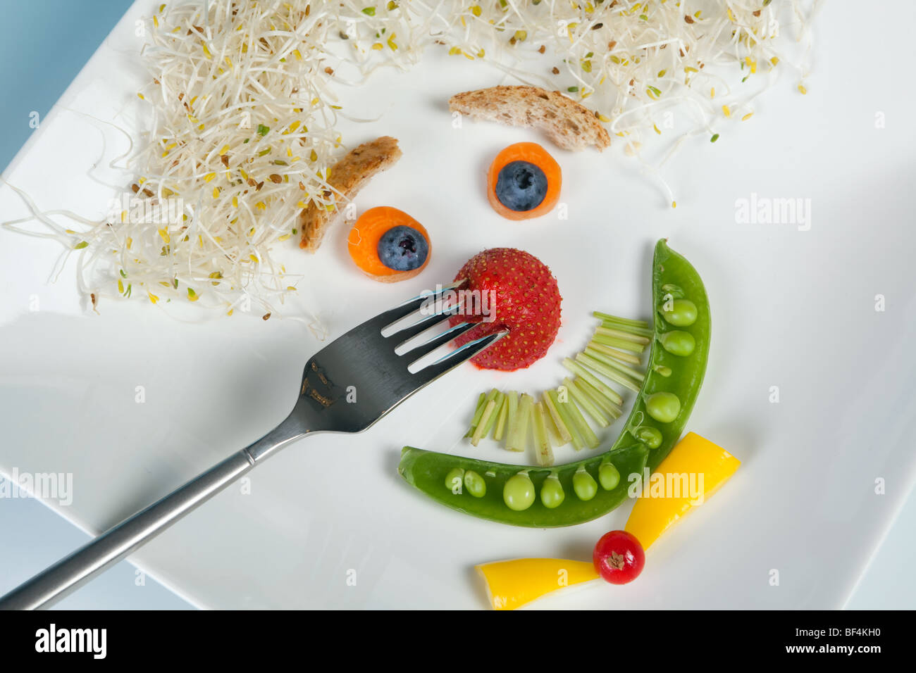 Funny food face with a fork in his strawberry nose Stock Photo - Alamy