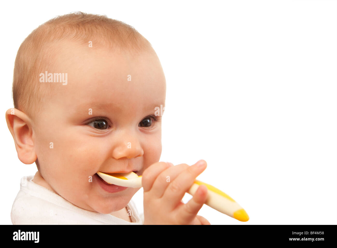 Baby putting spoon in his mouth. Isolated Stock Photo - Alamy