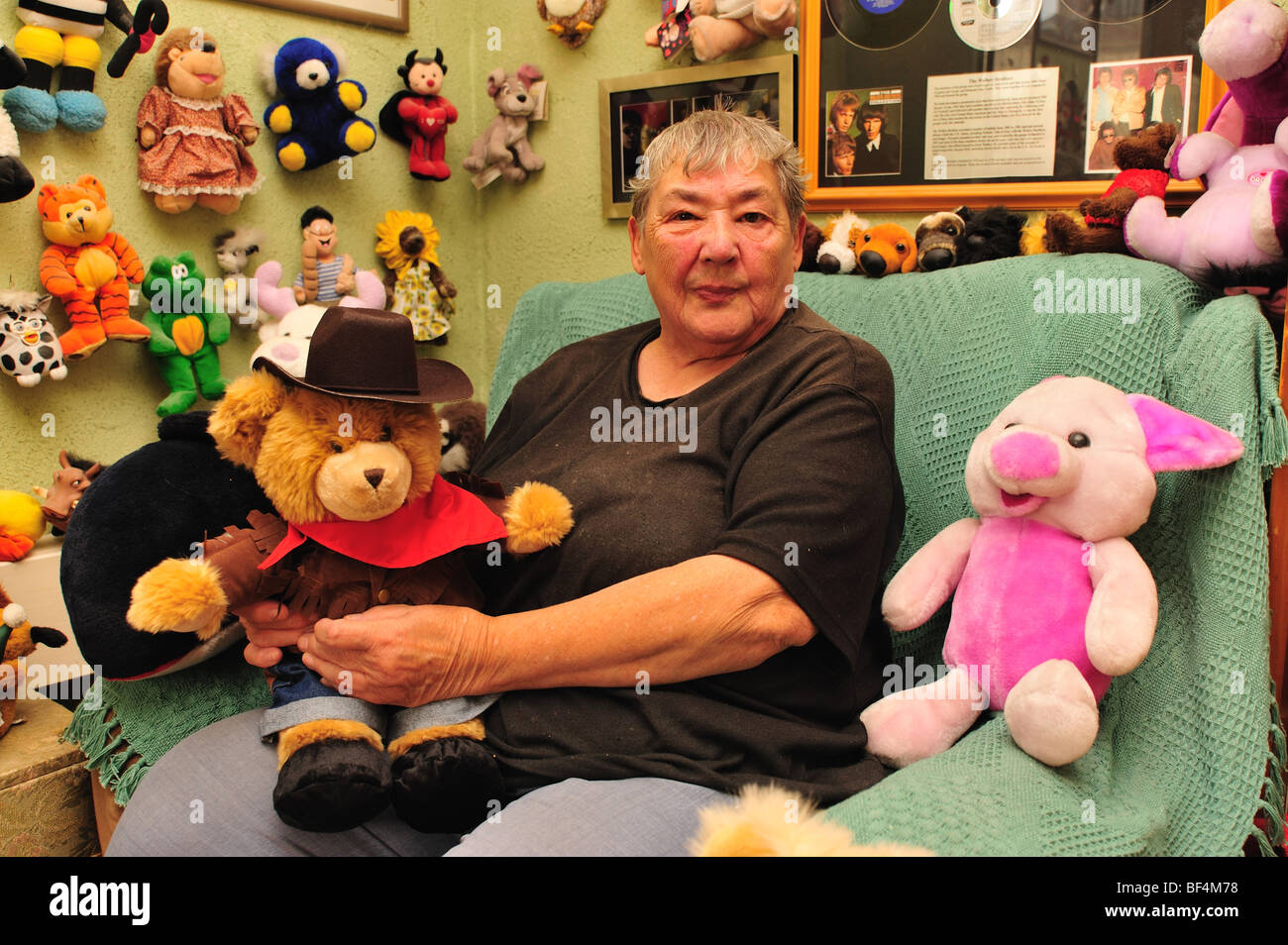 Elderly woman sitting with her soft toy collection in her living room ...