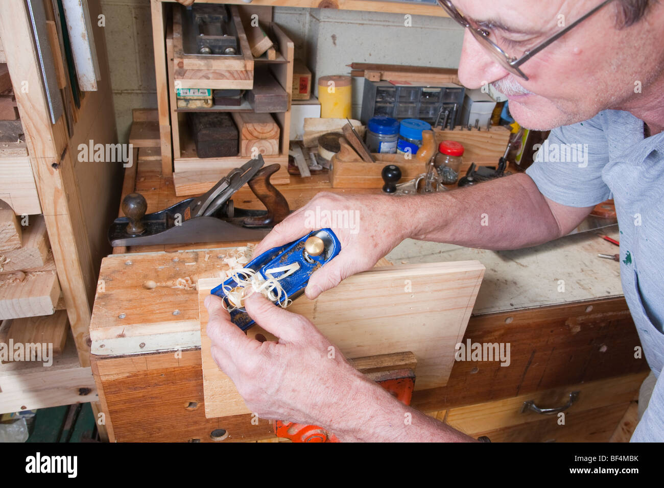 Senior man doing carpentry with edging plane on workbench Stock Photo ...