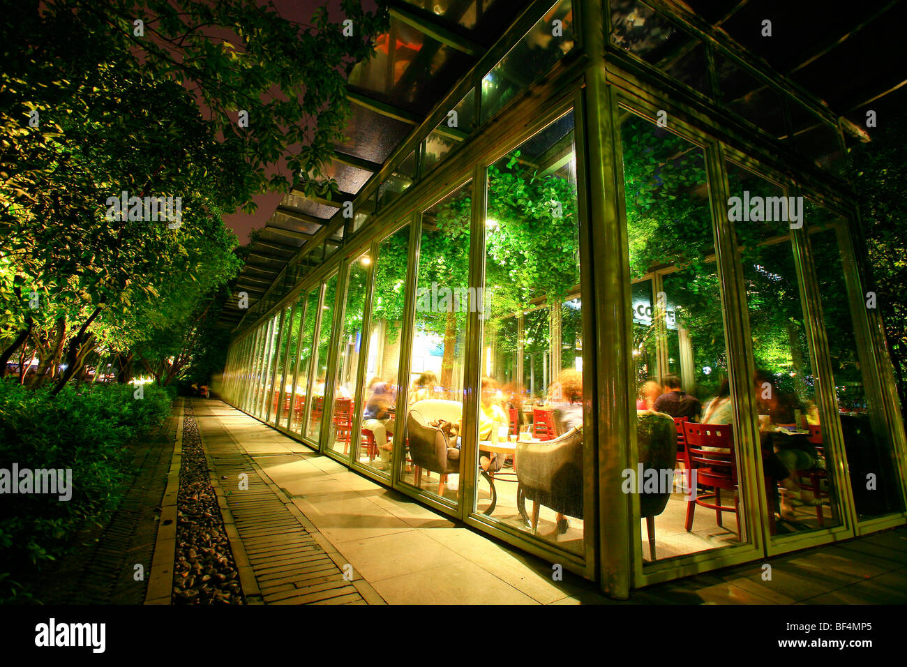 People enjoying dinner in glass room of a trendy restaurant, Hangzhou ...