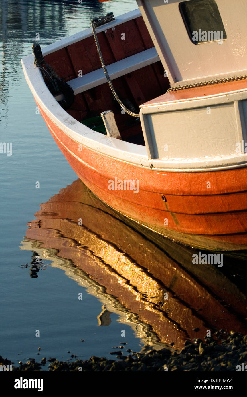 Side shot of a red fishing boat with its reflection in the water Stock ...