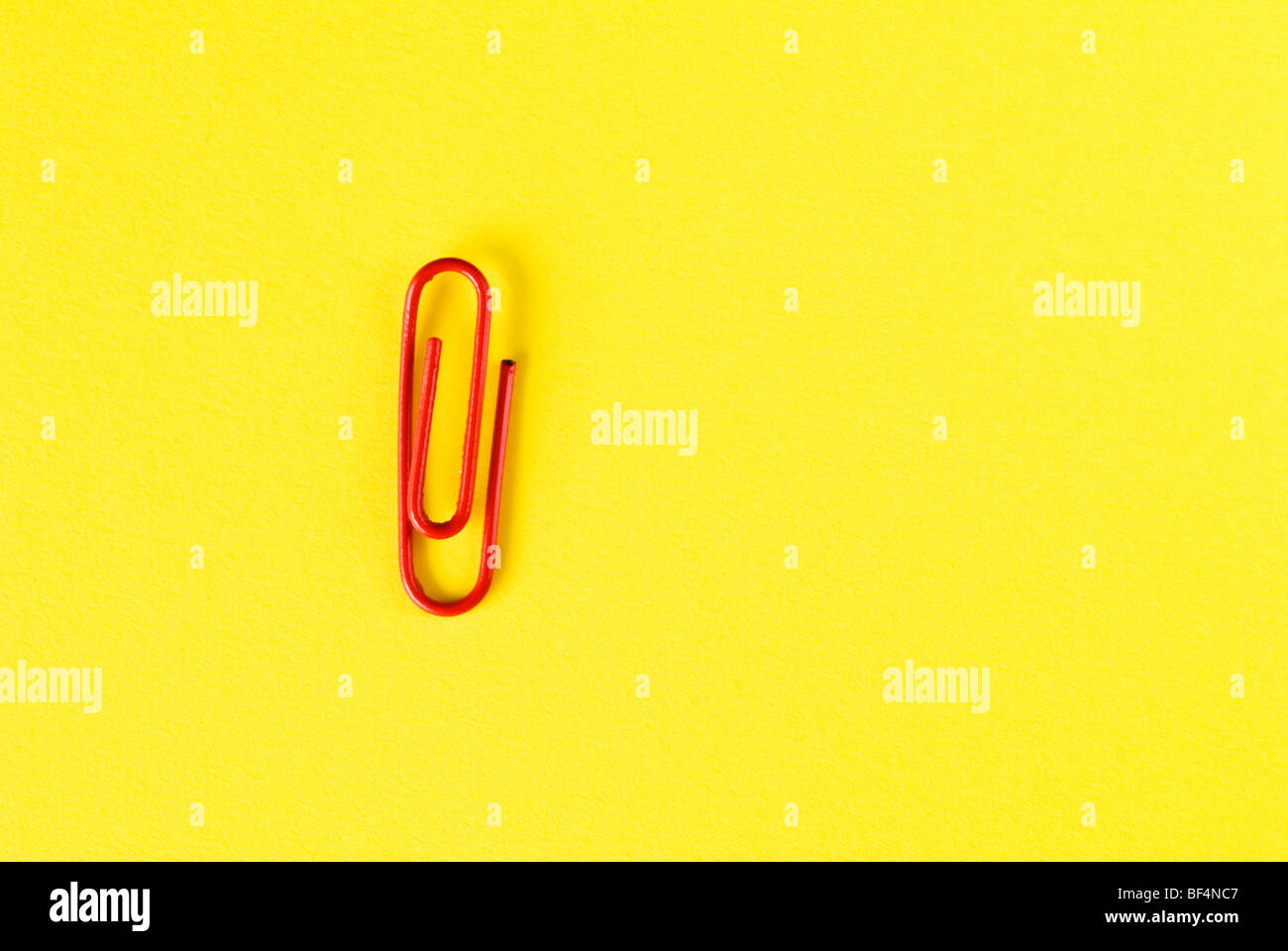 a red paper clip on a yellow blank background Stock Photo - Alamy