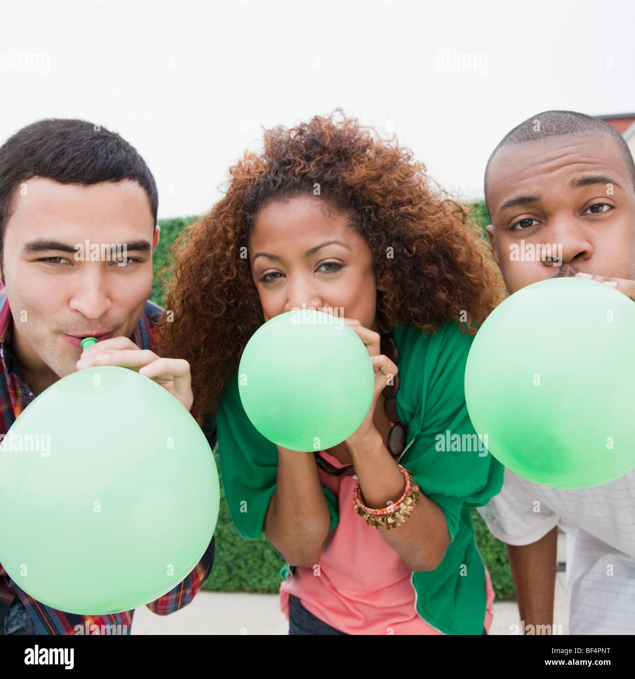 Friends blowing up green balloons Stock Photo - Alamy