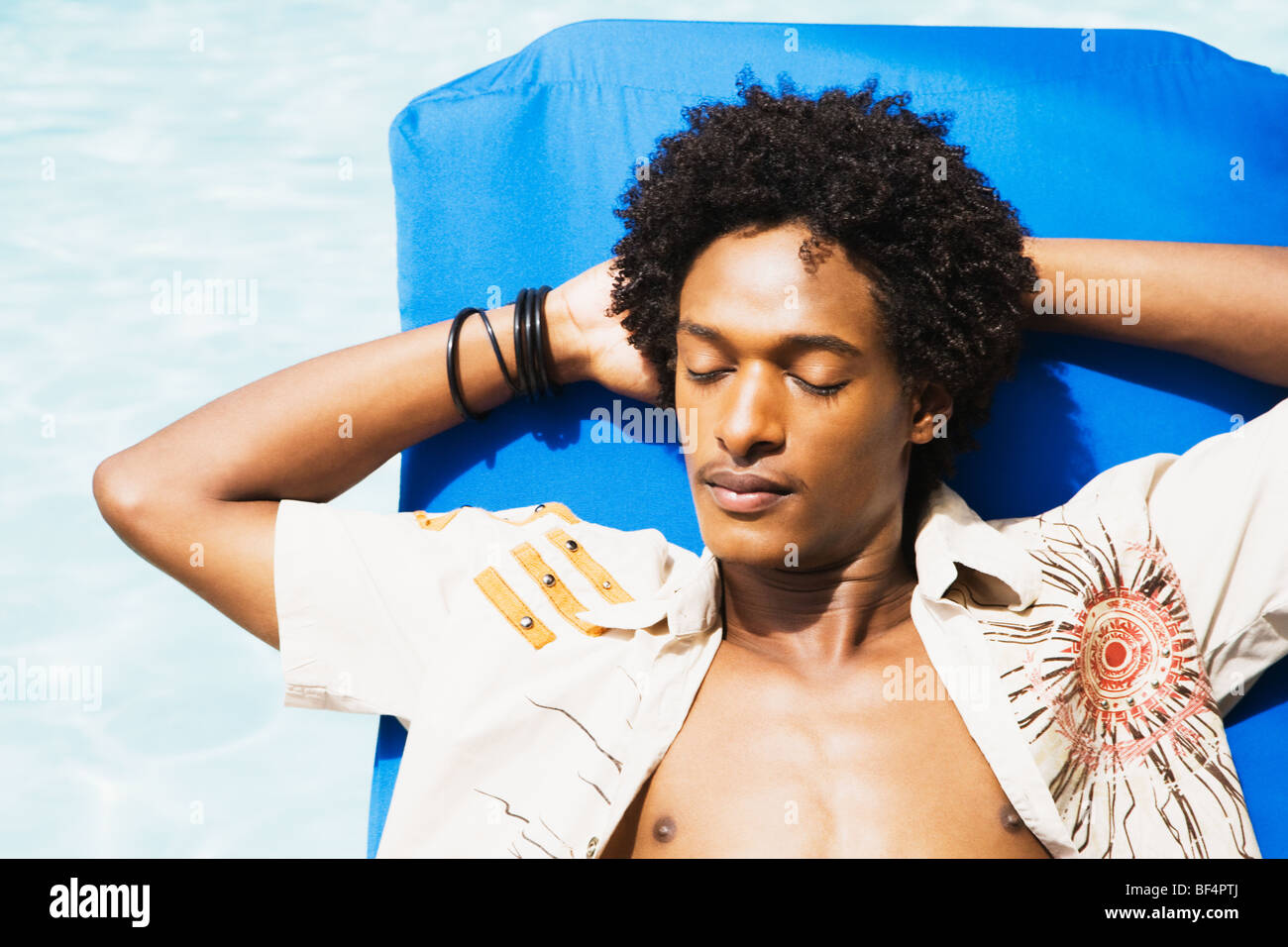African man laying in sun with eyes closed Stock Photo - Alamy