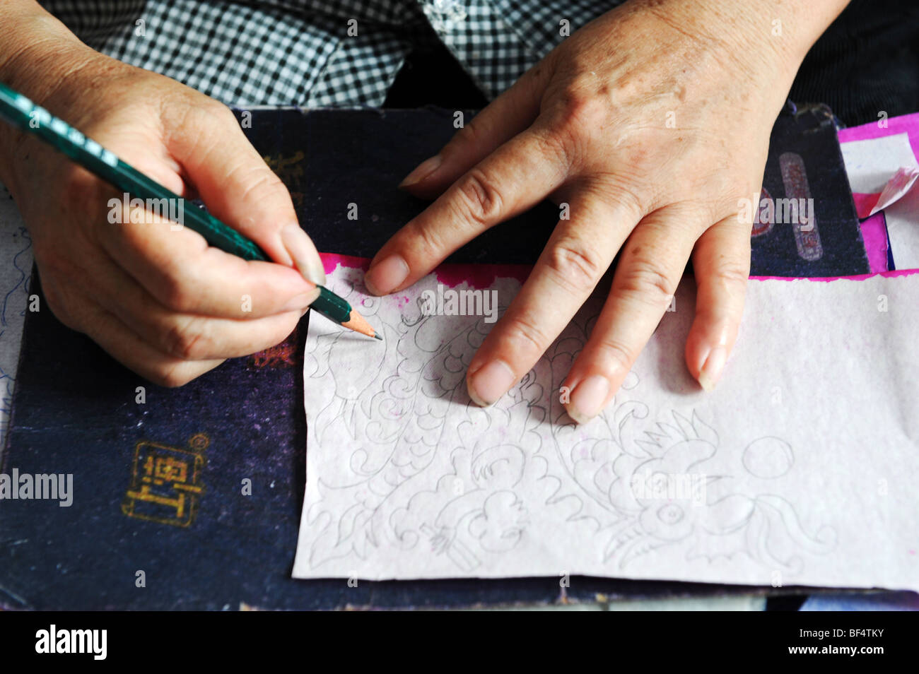 Craftsman drafting the pattern for paper-cut for embroidery, Taijiang ...