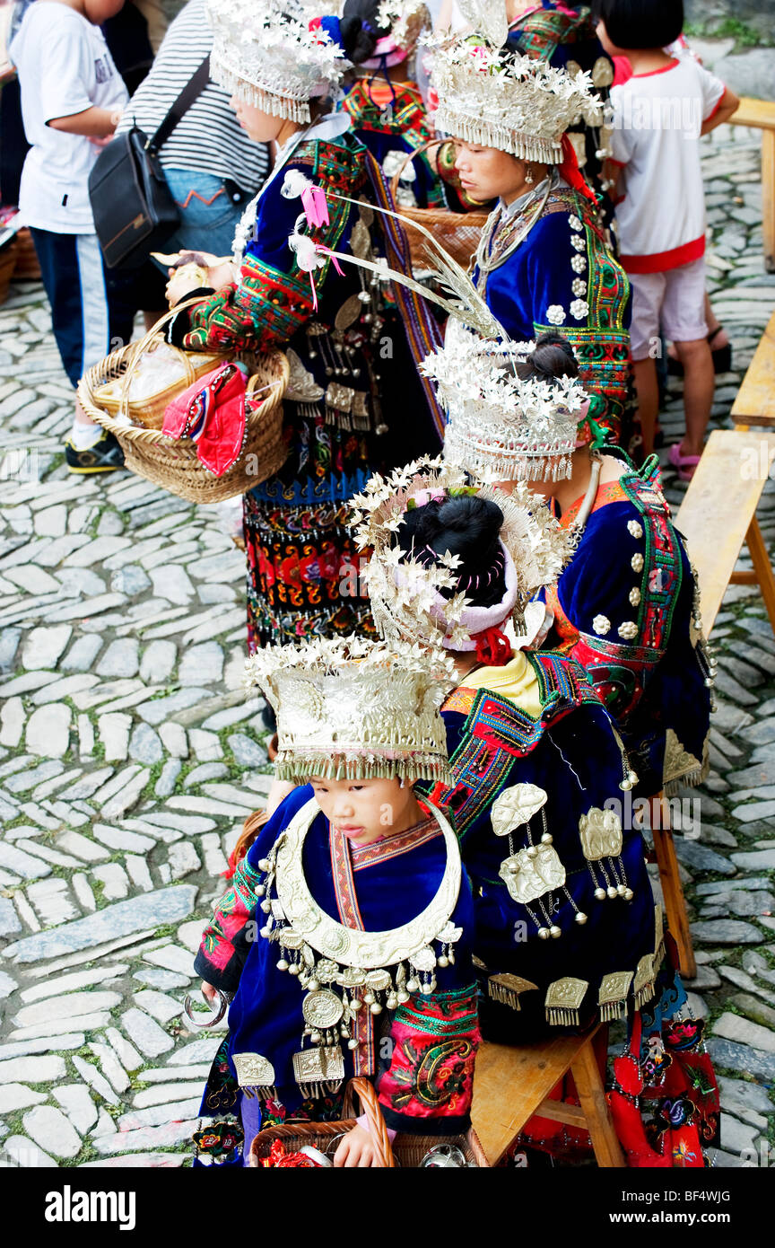 Miao street vendors sitting on wooden stool, Upper Langde Miao Village ...