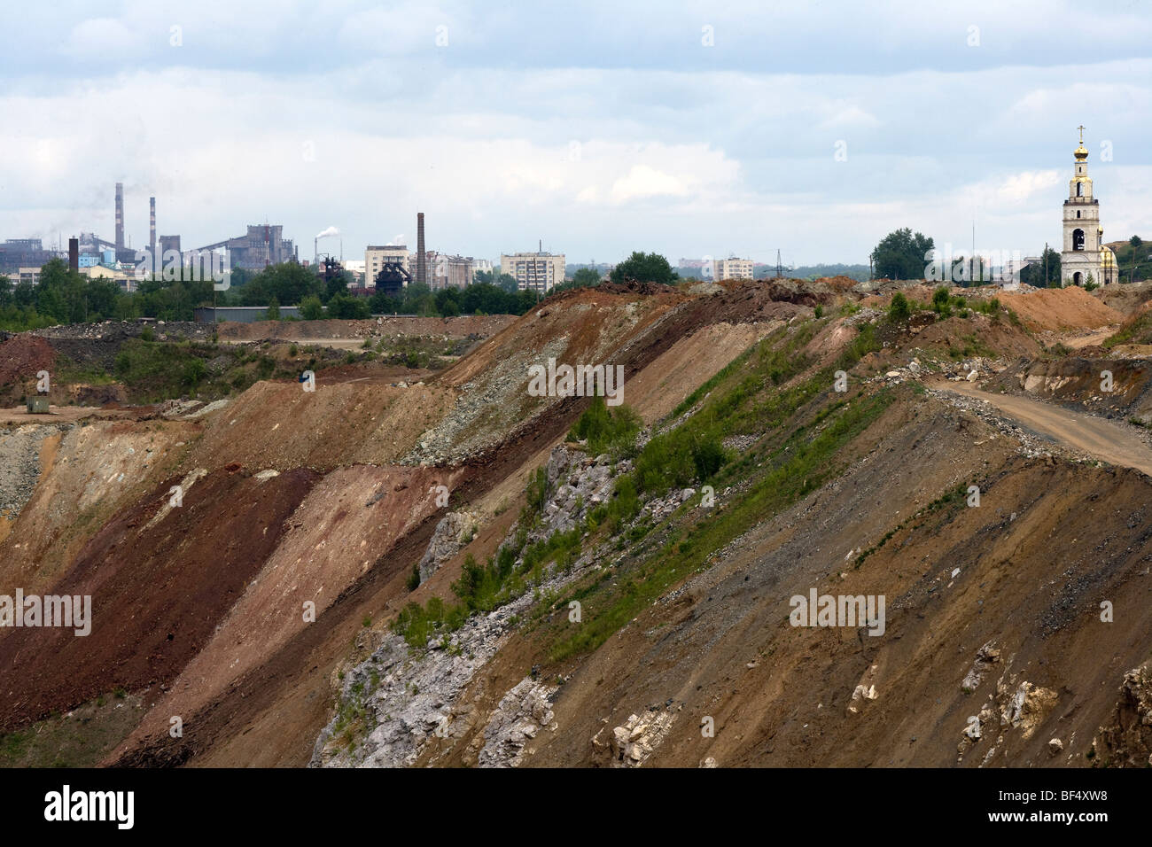 Industrial landscape with polluted slag heaps and distant city skyline ...