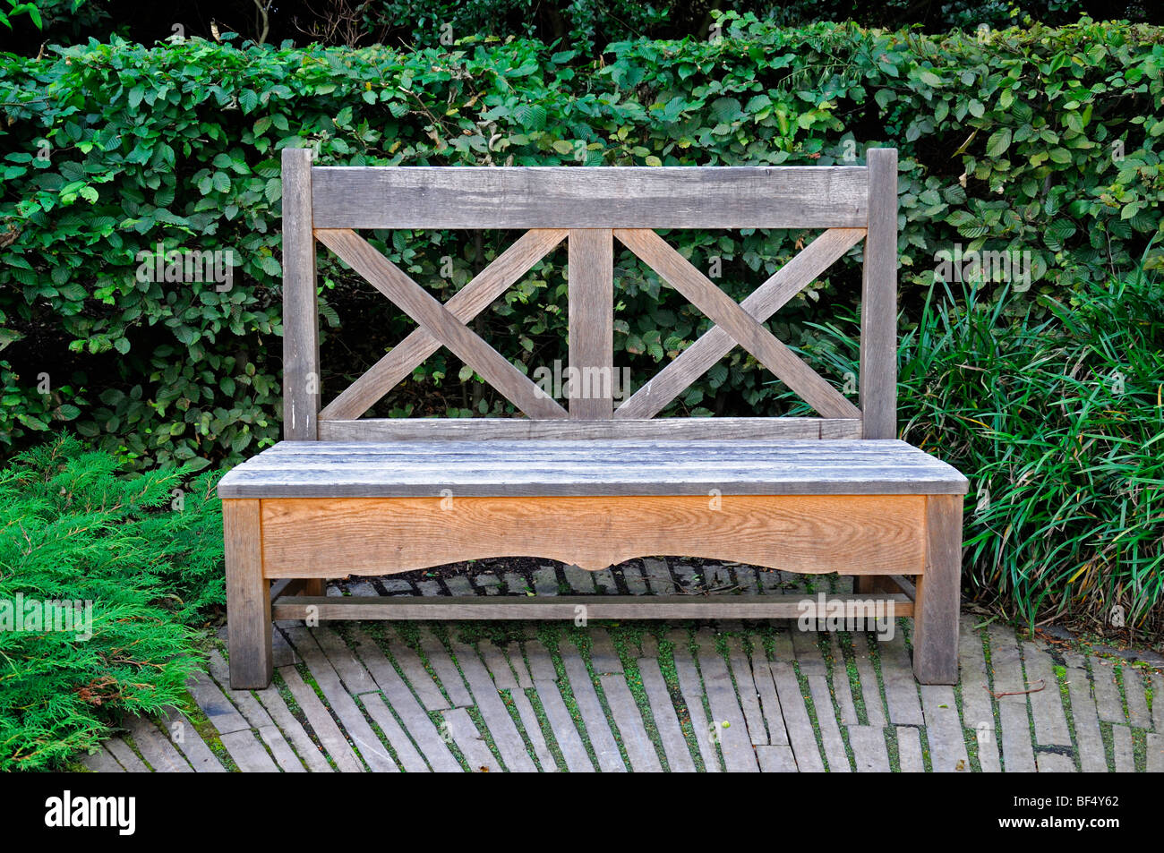 rustic wooden wood garden seat formal in front of green leaf leafed ...