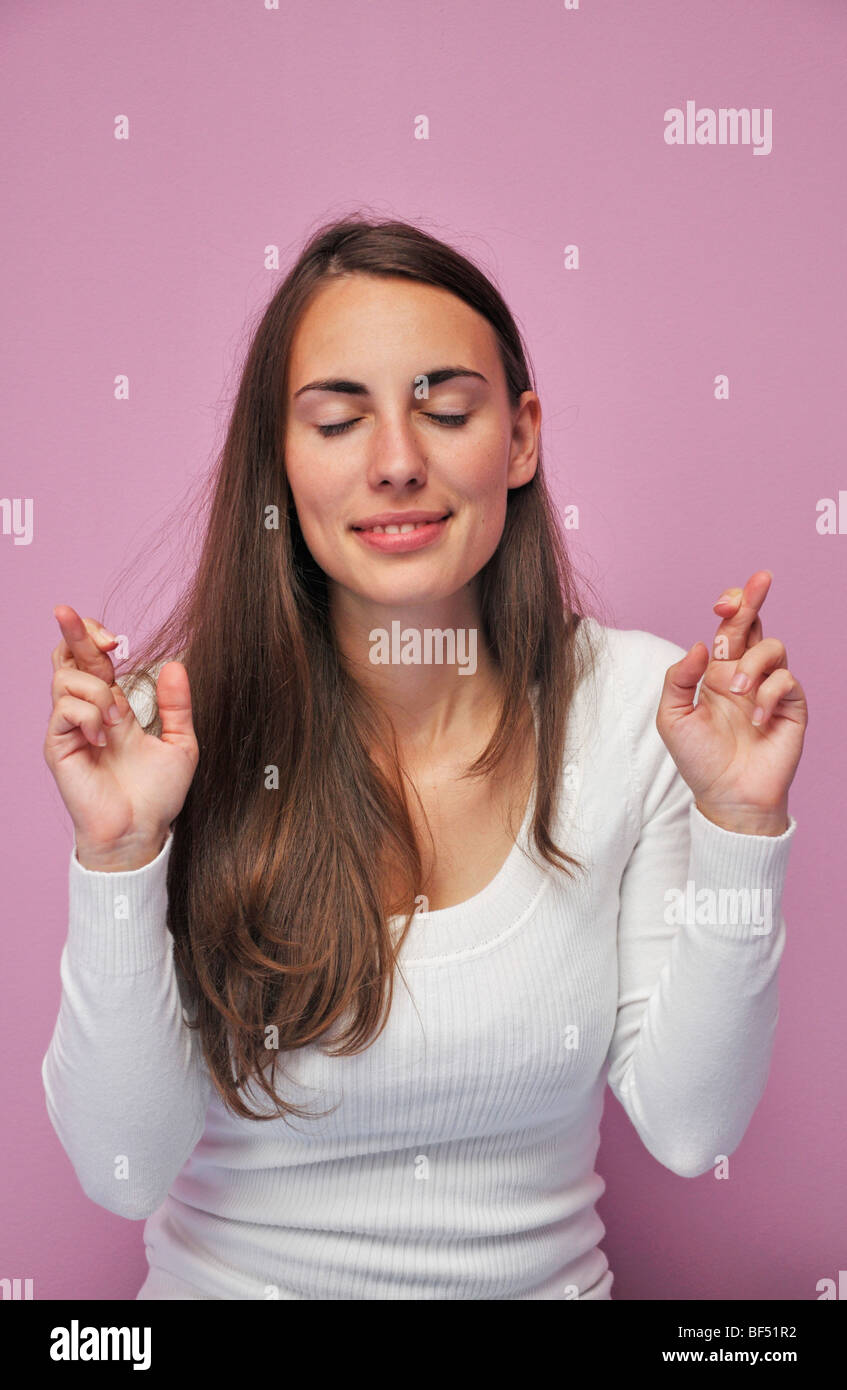 Young woman with fingers crossed Stock Photo - Alamy