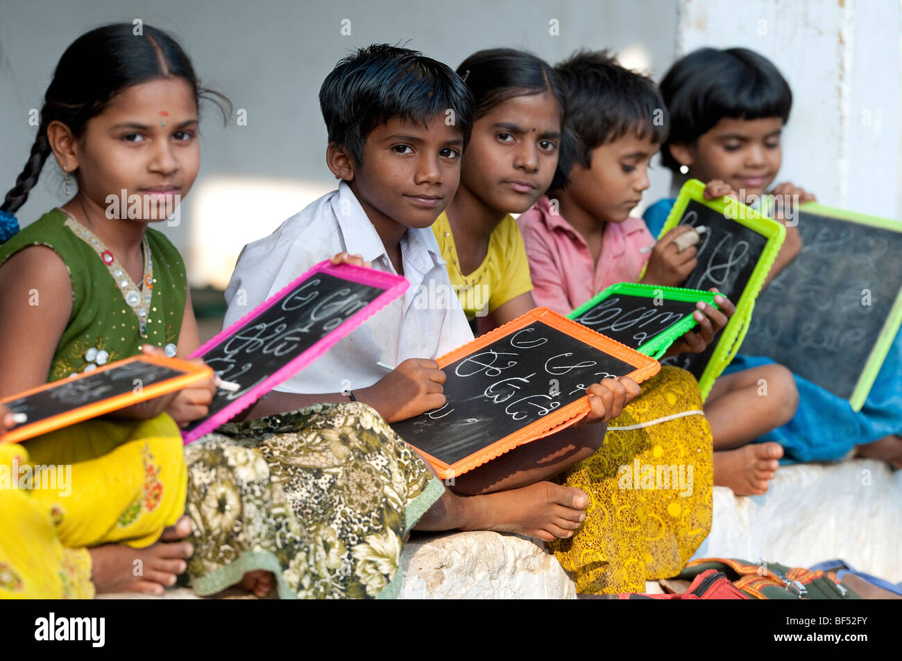 Indian school children sitting outside their school writing on ...