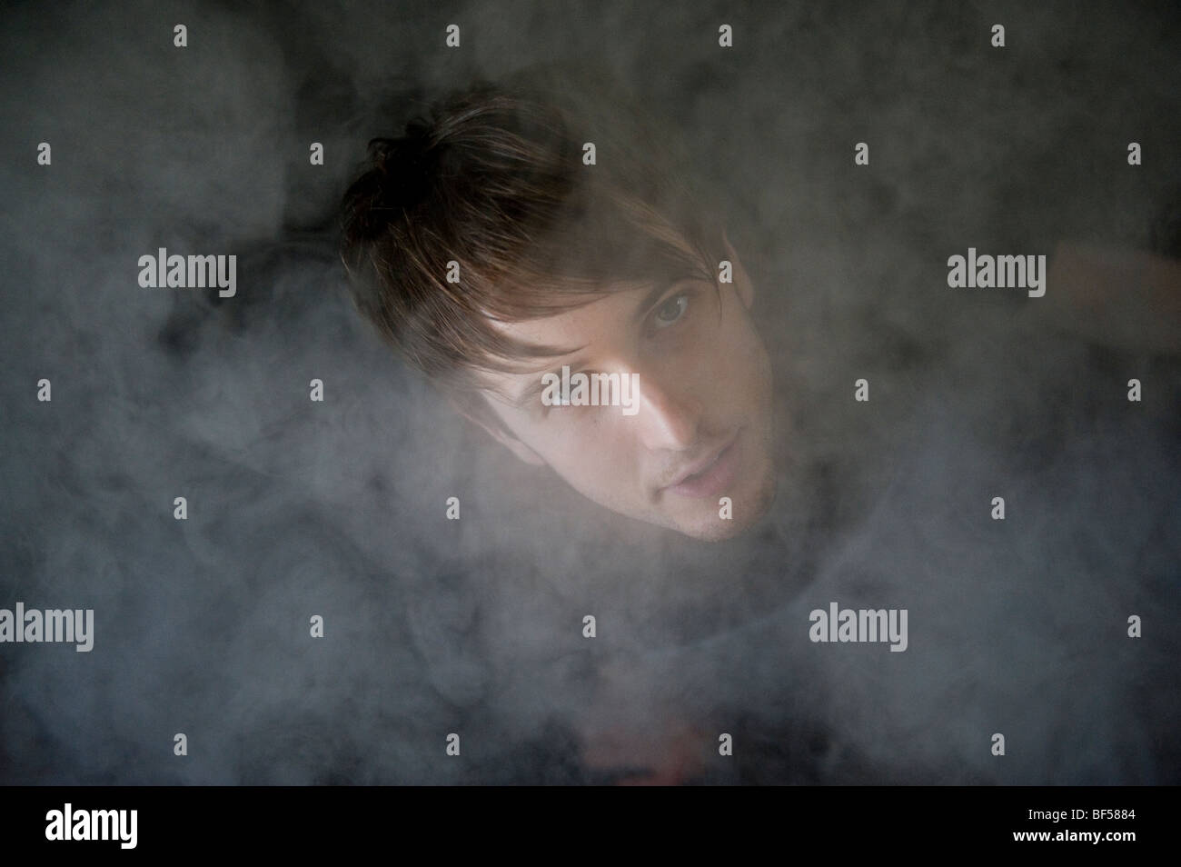 A young man poses in a smoky atmosphere Stock Photo - Alamy