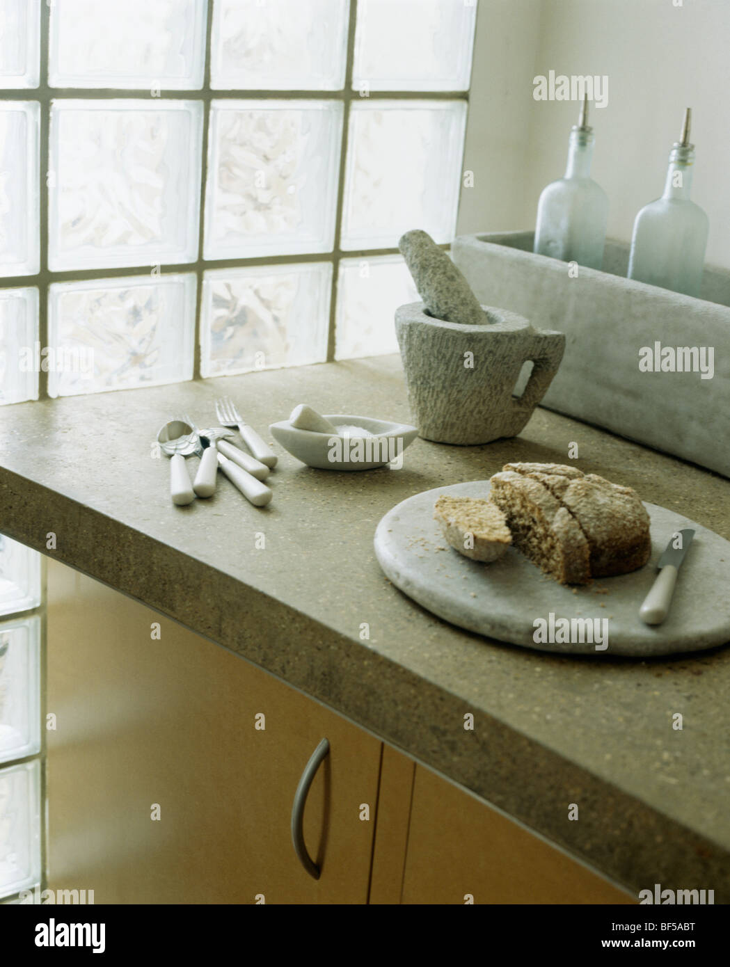 Close-up of stone pestle+mortar and circular marble breadboard on stone ...