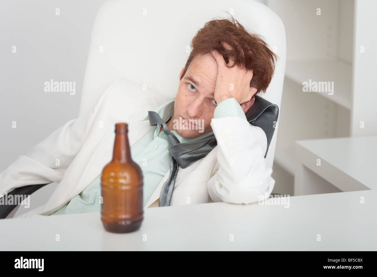 The young drunken man at office with a beer bottle Stock Photo - Alamy