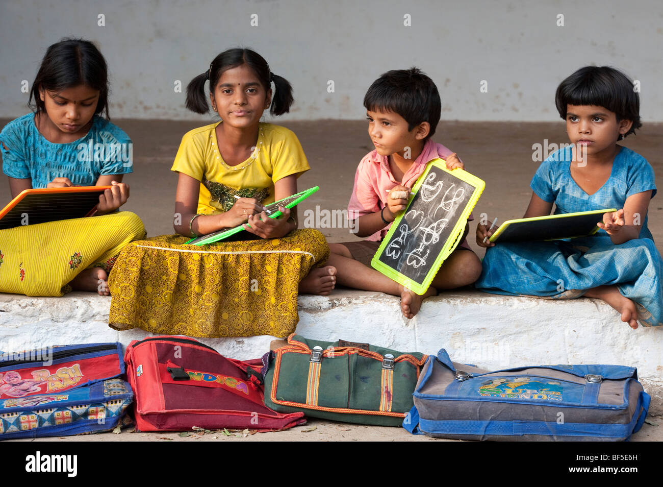 Indian school children sitting outside their school writing on ...