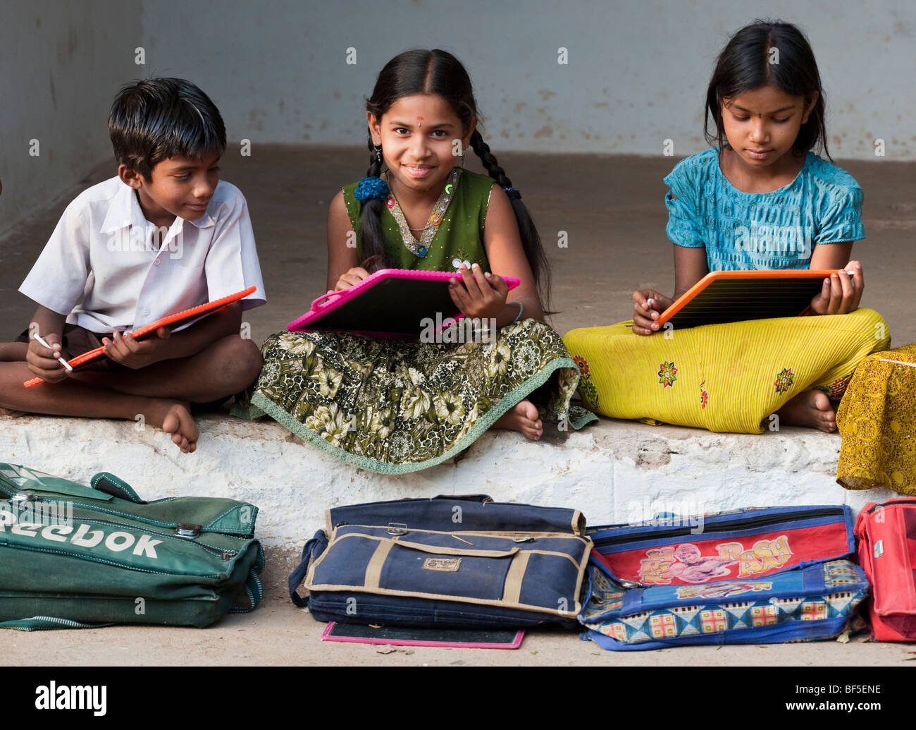 Indian school children sitting outside their school writing on ...
