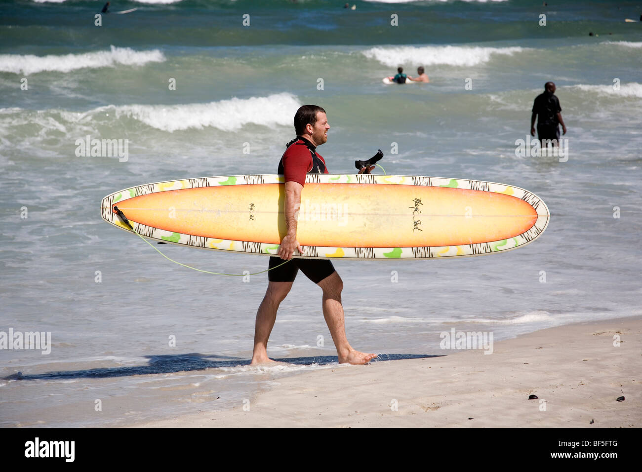 Surfer carrying board on Muizenberg Beach - Cape Town Stock Photo - Alamy