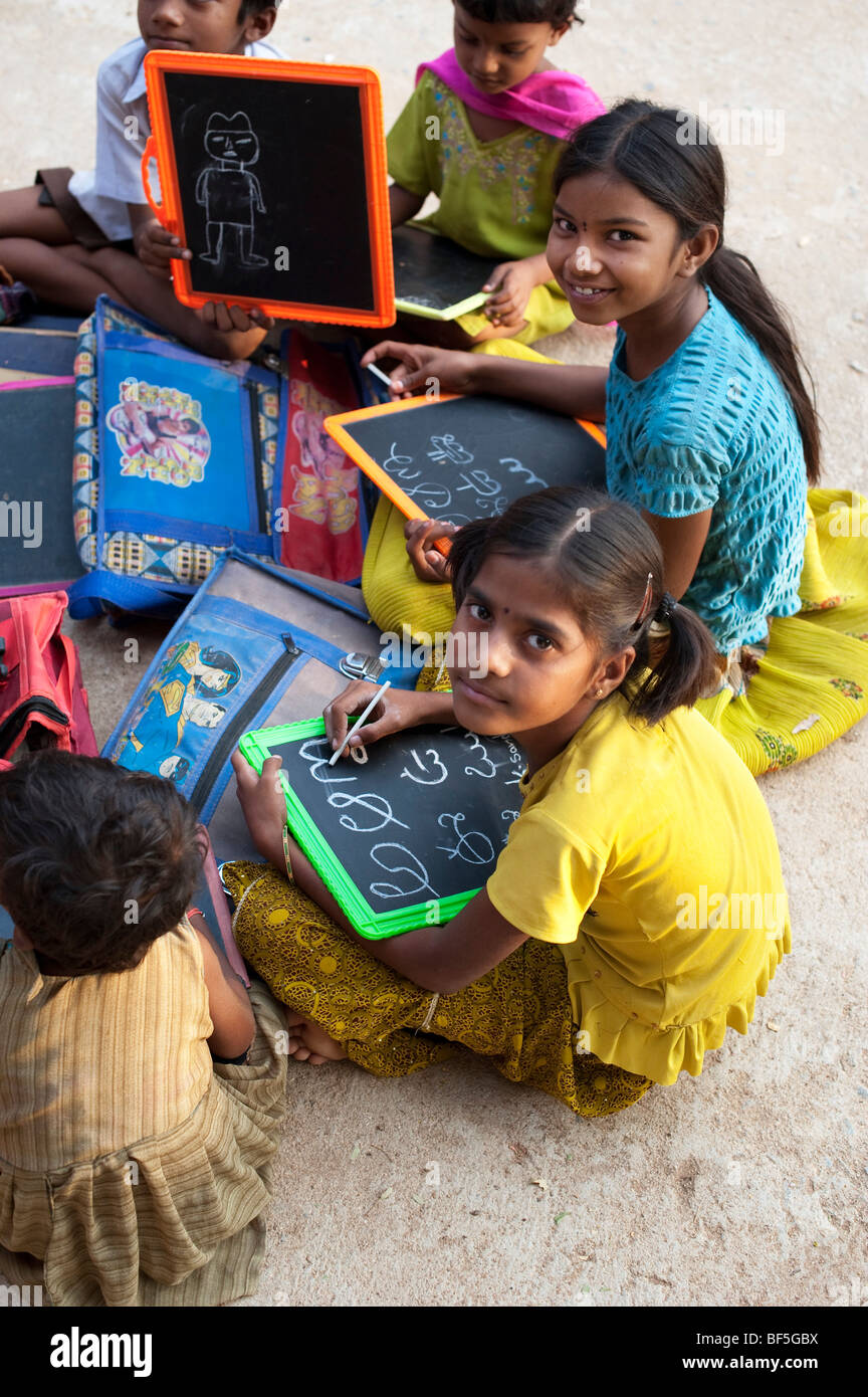 Indian school children sitting outside their school writing on ...