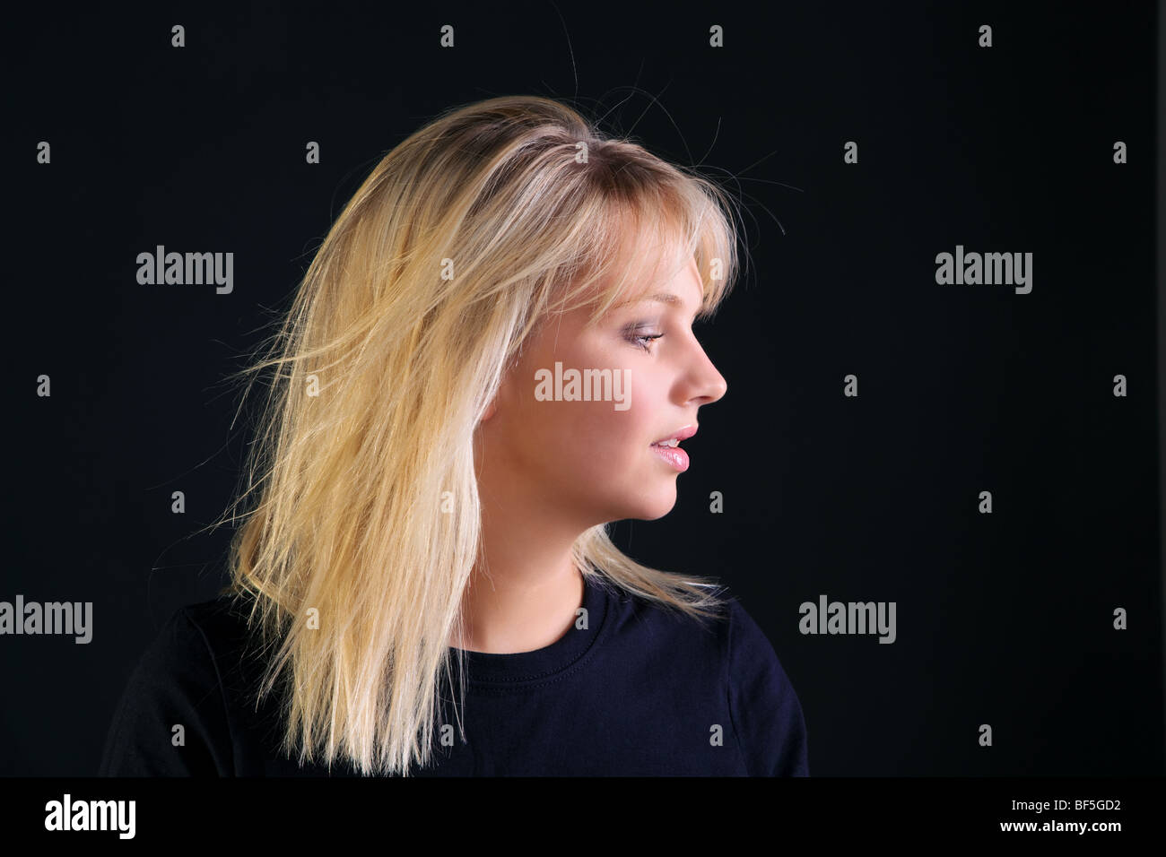 Portrait of a beautiful blonde haired woman with blue eyes on a black ...