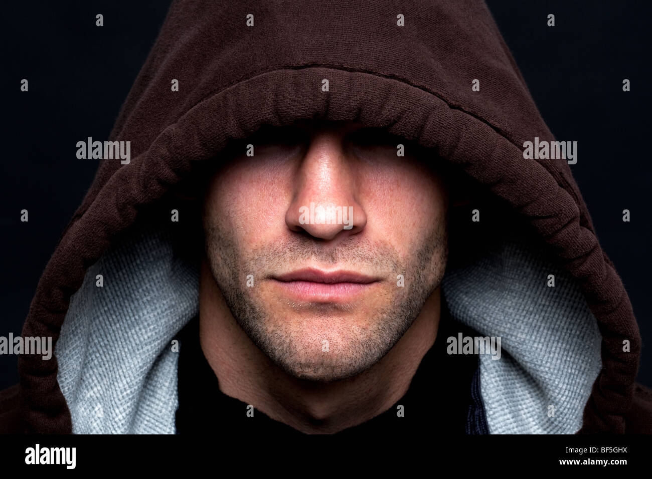 An evil looking man wearing a hooded top with his eyes hidden against a ...
