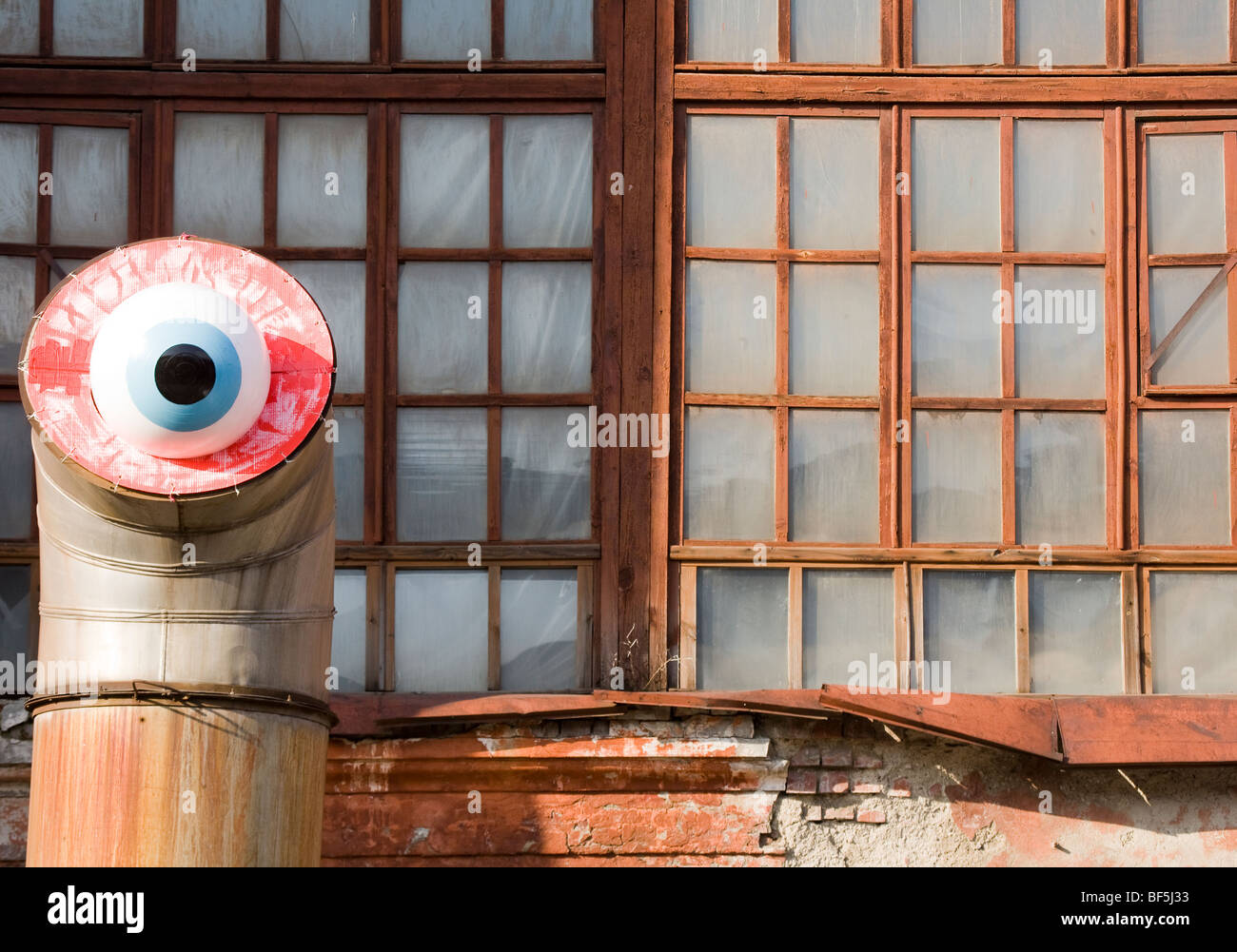 Eyeball sculpture on industrial pipe outside industrial building ...
