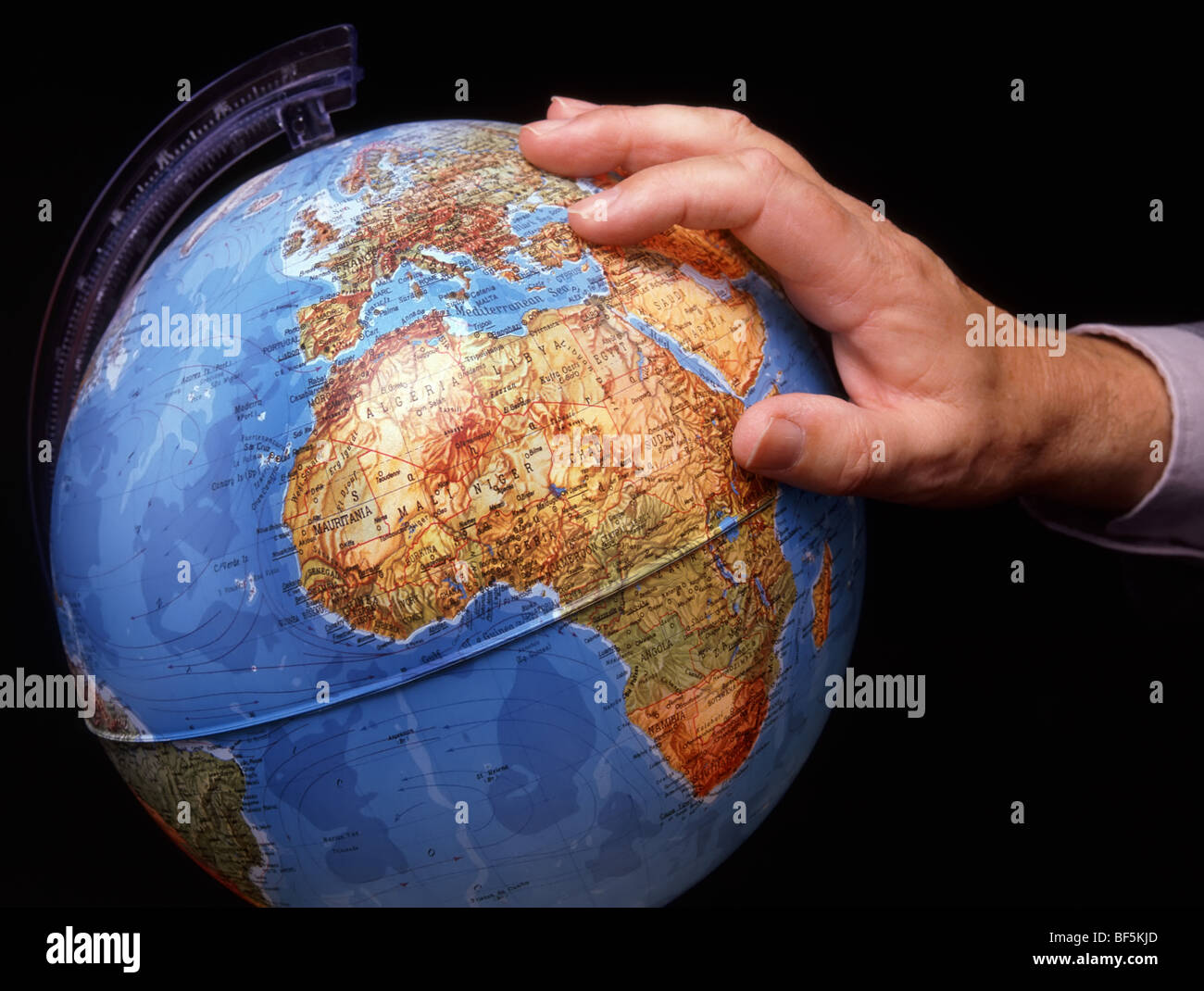 Close up male hand on world globe concept image getting a grip on wider ...