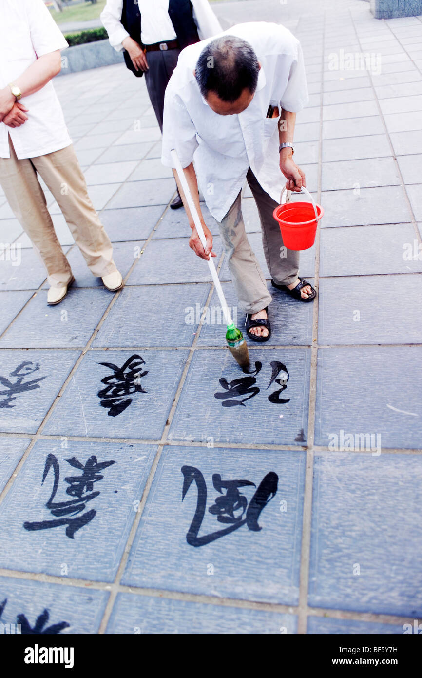 Elderly man practicing calligraphy with big brush on ground, Yichang ...