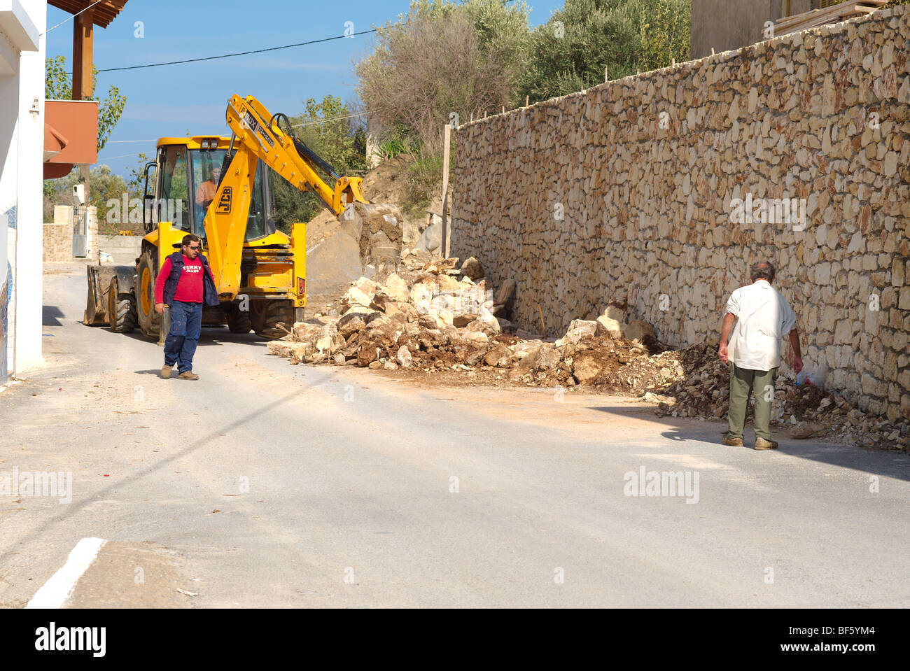 JCB clearing rocks from road Stock Photo - Alamy