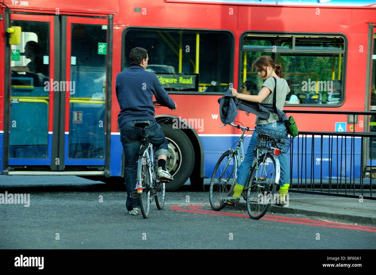 Male and female cyclist at junction waiting for Bus to pass, Central ...