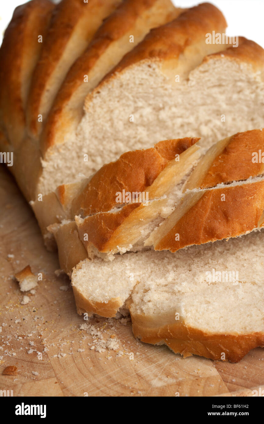 fresh white crusty bloomer loaf cut into rough slices on a wooden block ...