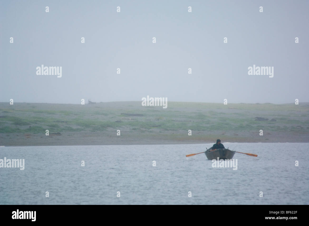 Fisherman in small dory boat in the rain and fog on Big Lagoon ...