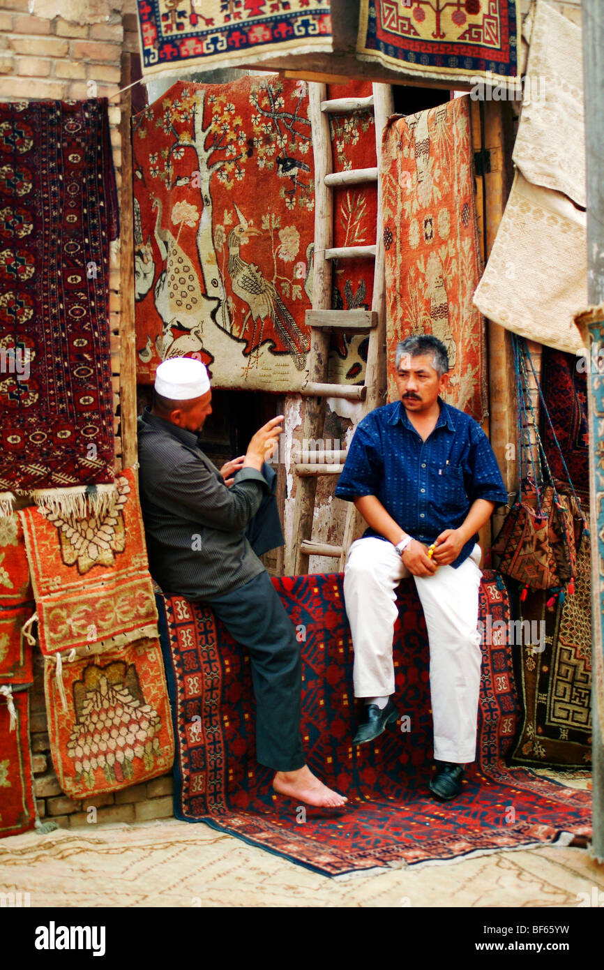 Uigur men in modern costume selling carpet, Urumqi, Xinjiang Uyghur ...