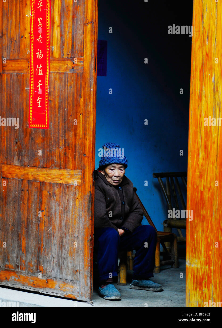 Elderly Chinese woman sitting in the doorway of traditional home ...