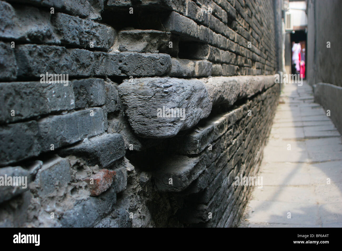 Broken gray brick wall of a traditional courtyard house and narrow ...